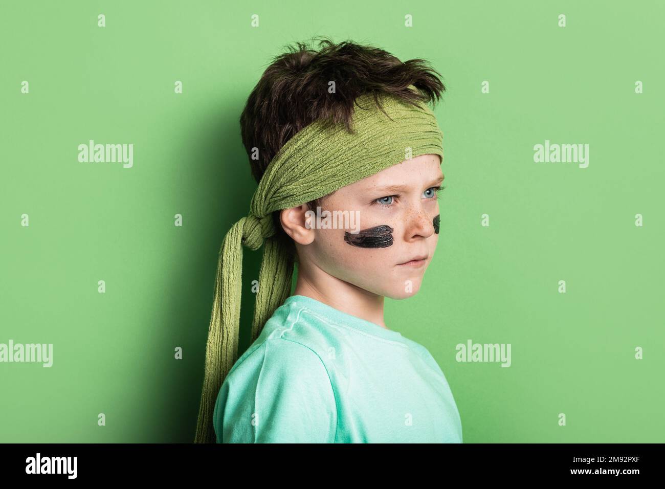 Kid in casual clothes with green headband with black strips on face ...