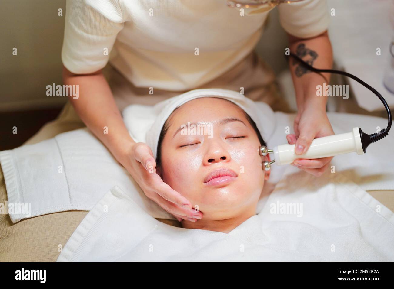 High angle of crop anonymous cosmetician doing microcurrent therapy on ...