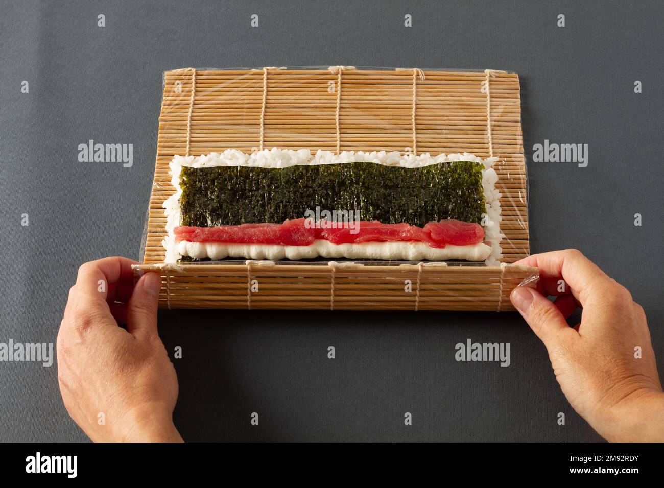 From above of crop anonymous person making sushi with rolling mat ...