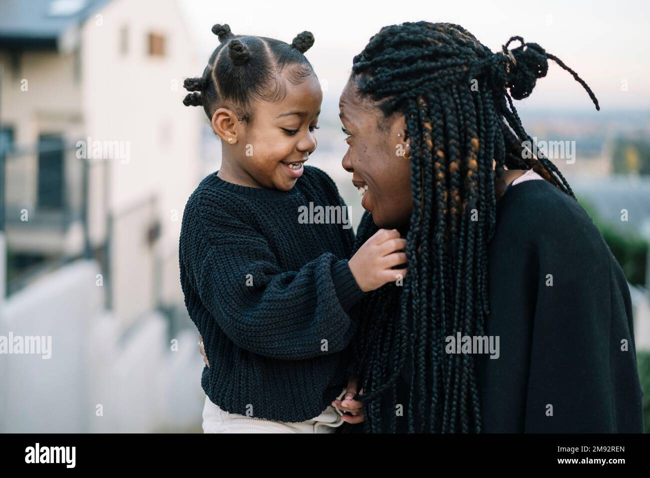 Side view of loving African American mother embracing little girl in ...