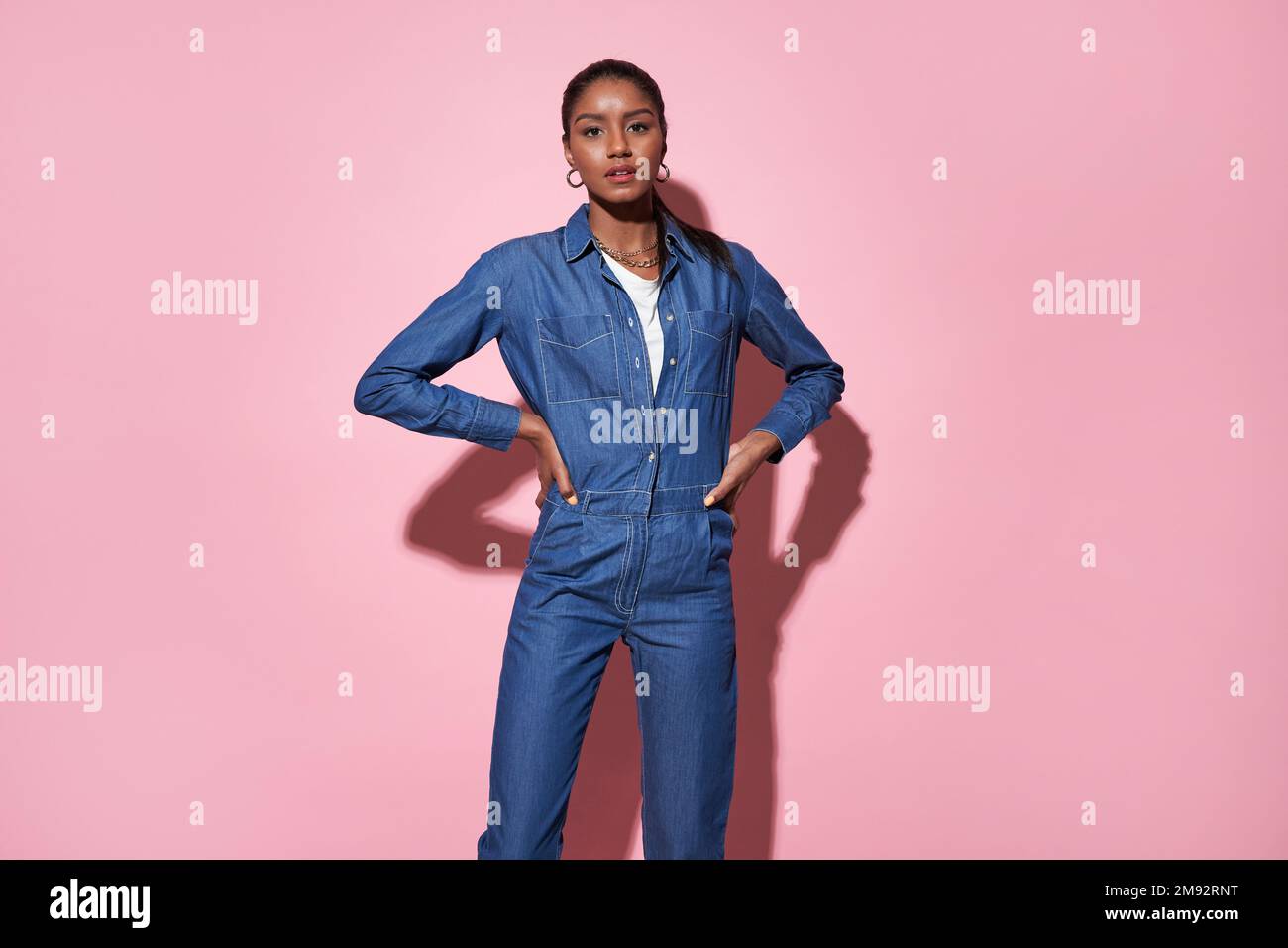 Serious young African American female in denim outfit standing against ...