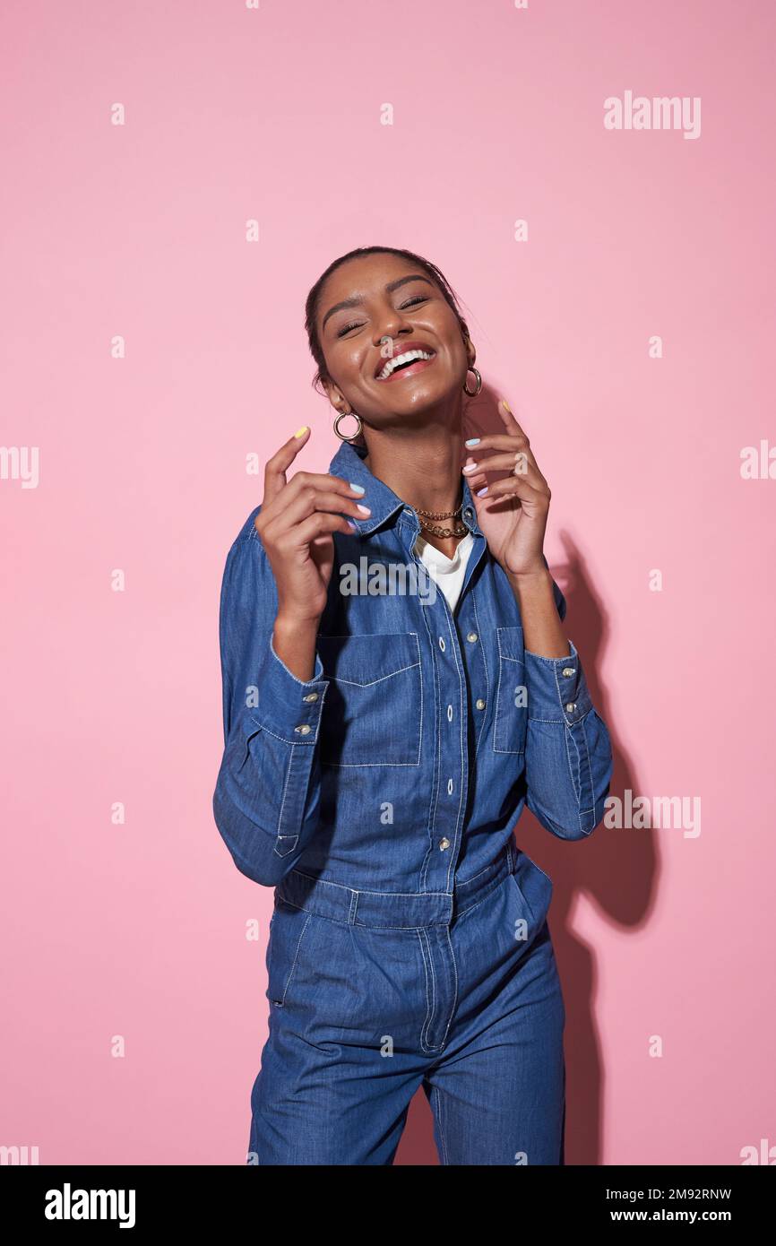 Optimistic young African American female model smiling and pointing at ...