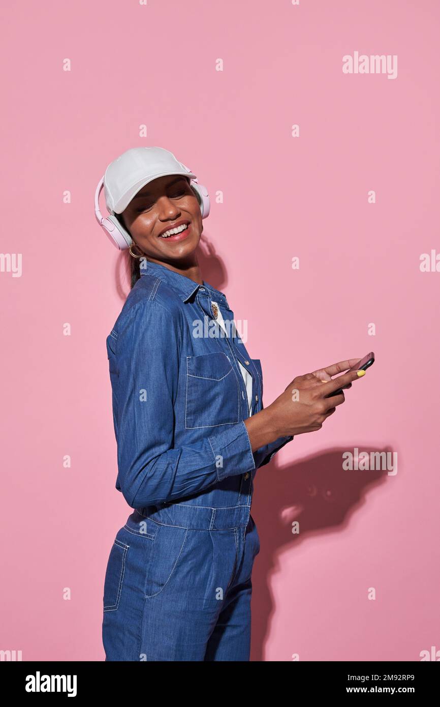 Optimistic young African American female in cap and denim overall ...