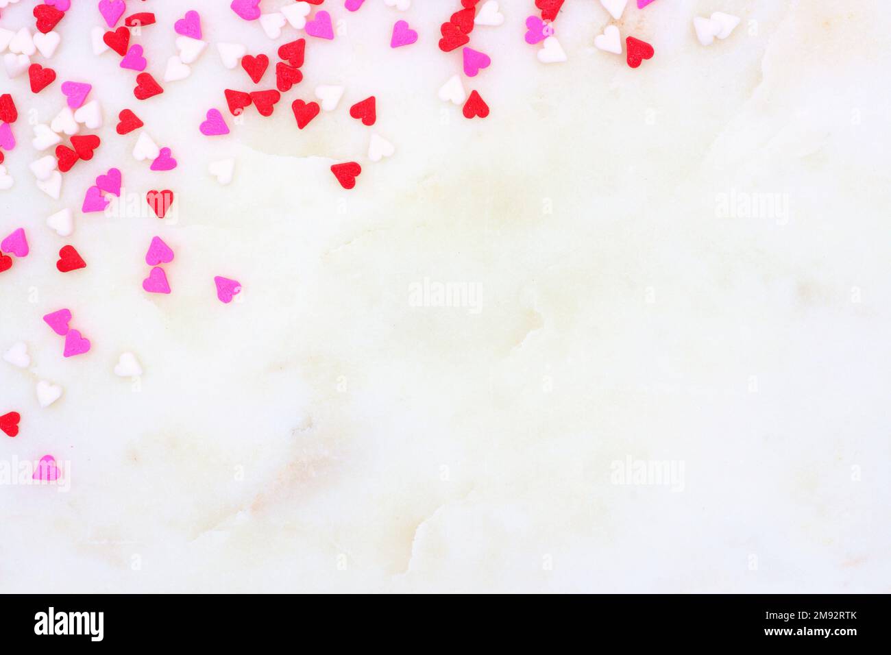 Valentines Day candy heart sprinkles corner border over a white marble ...