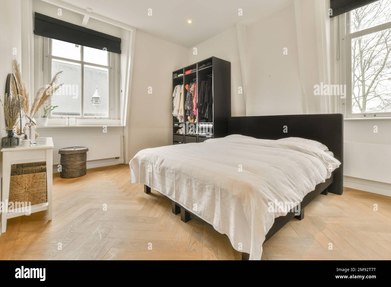 Comfortable bed next to a bright window and wooden floor Stock Photo ...