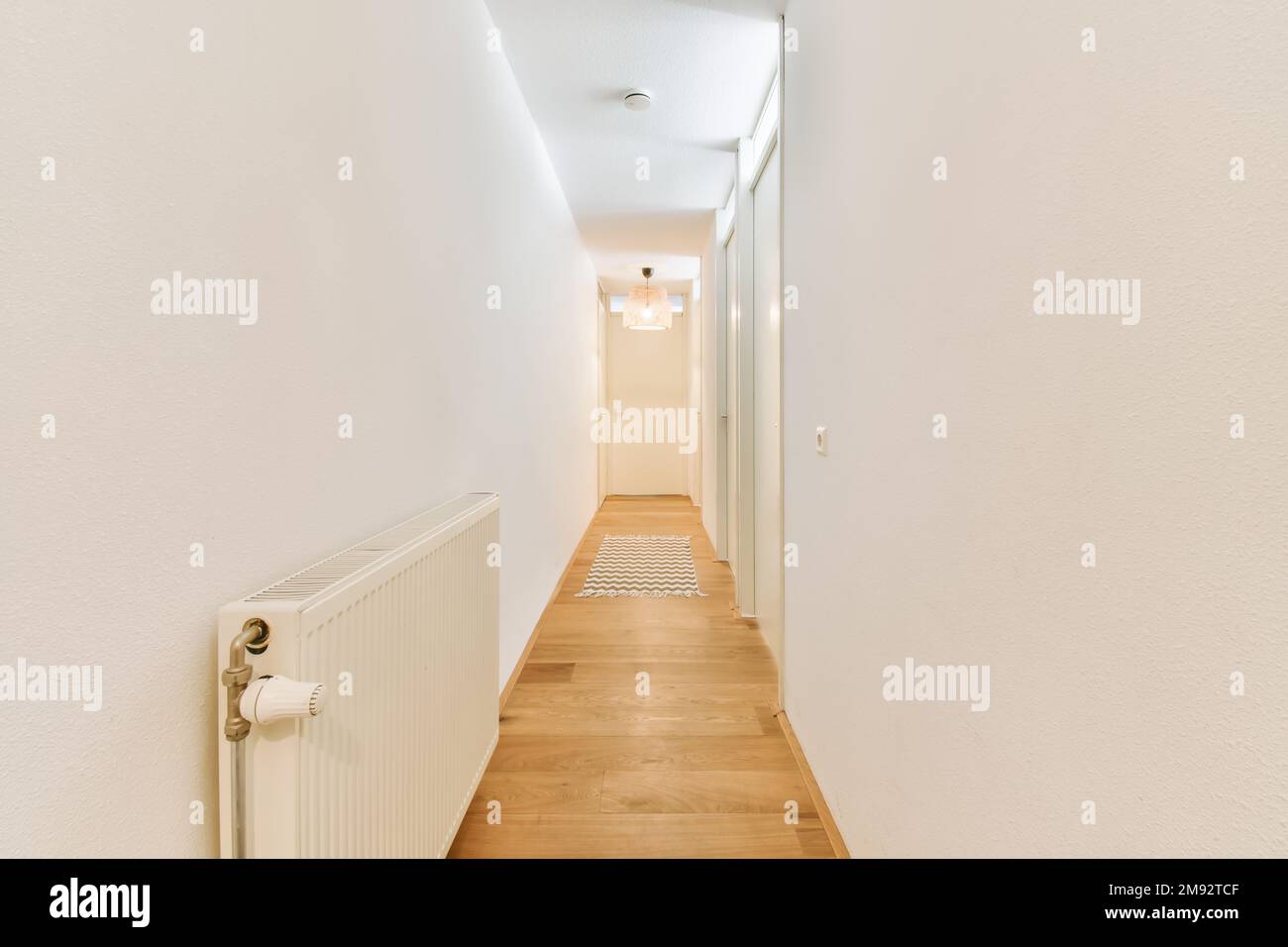 Perspective view of narrow hallway with white walls and wooden floor in ...