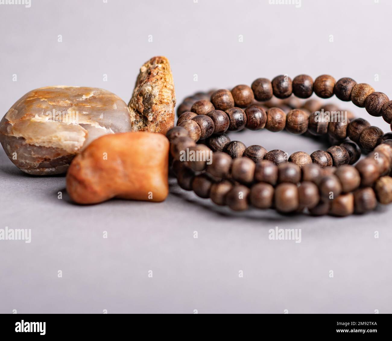 The wooden Mala prayer beads, placed near stones, isolated on a purple ...