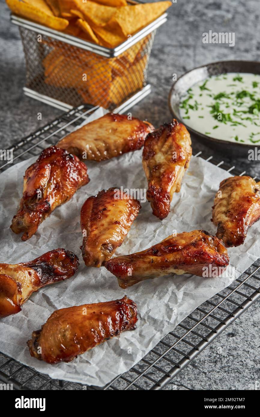 High angle of buffalo chicken wings with pepper sauce served with chips ...