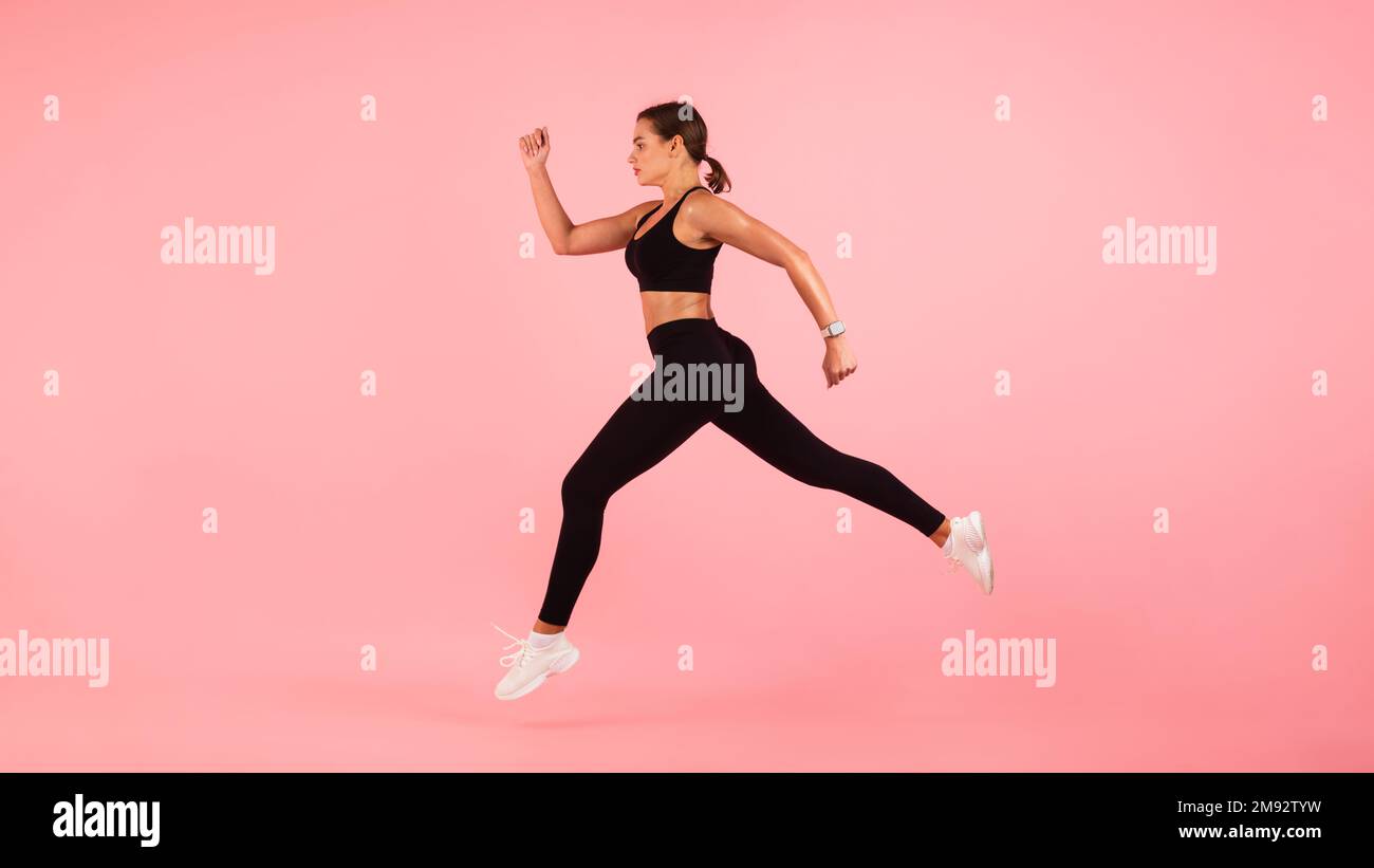 Motivated Sporty Young Woman Running In Mid-Air Over Pink Background ...