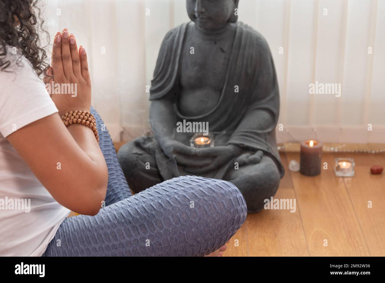 Crop anonymous female in casual clothes sitting on floor with namaste ...