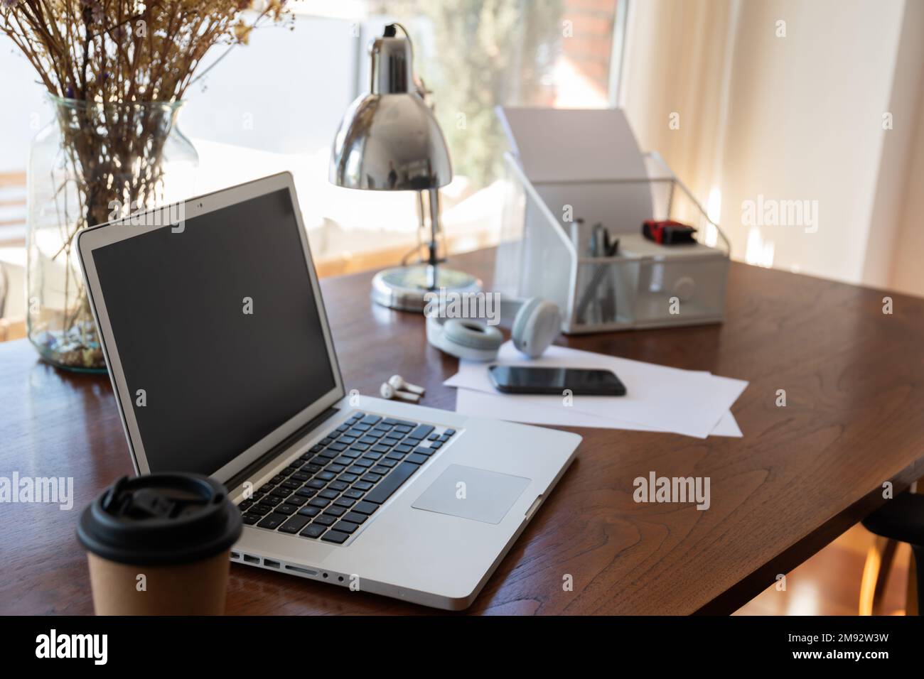 Interior of modern home workspace with wooden table and laptop and chair near big window in ...