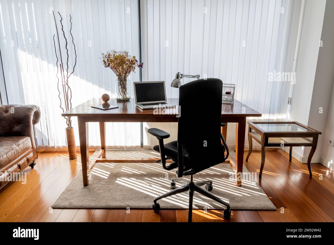 Interior of modern home workspace with wooden table and laptop and chair near big window in ...