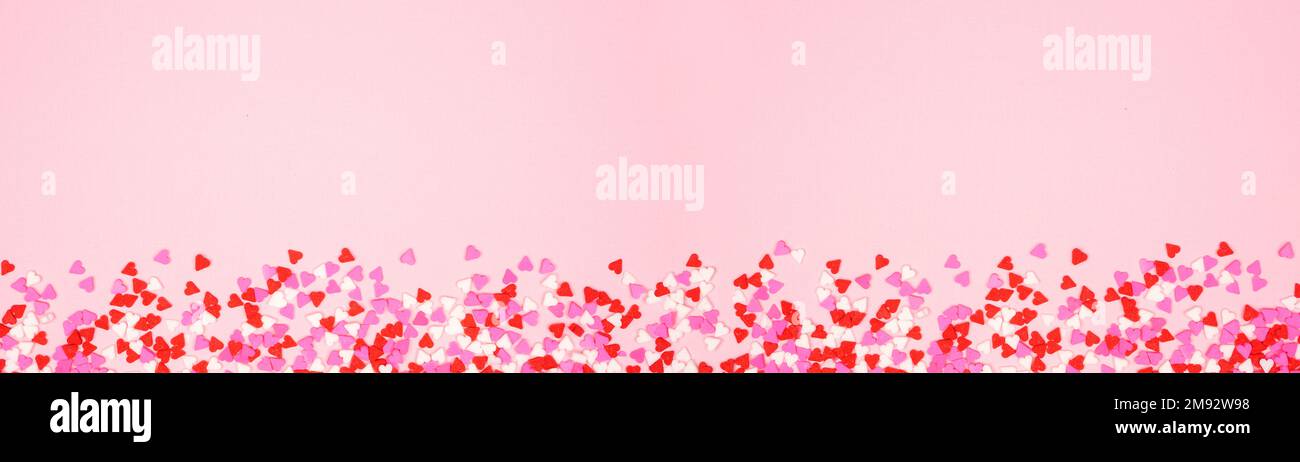 Valentines Day long border banner with candy heart sprinkles over a ...