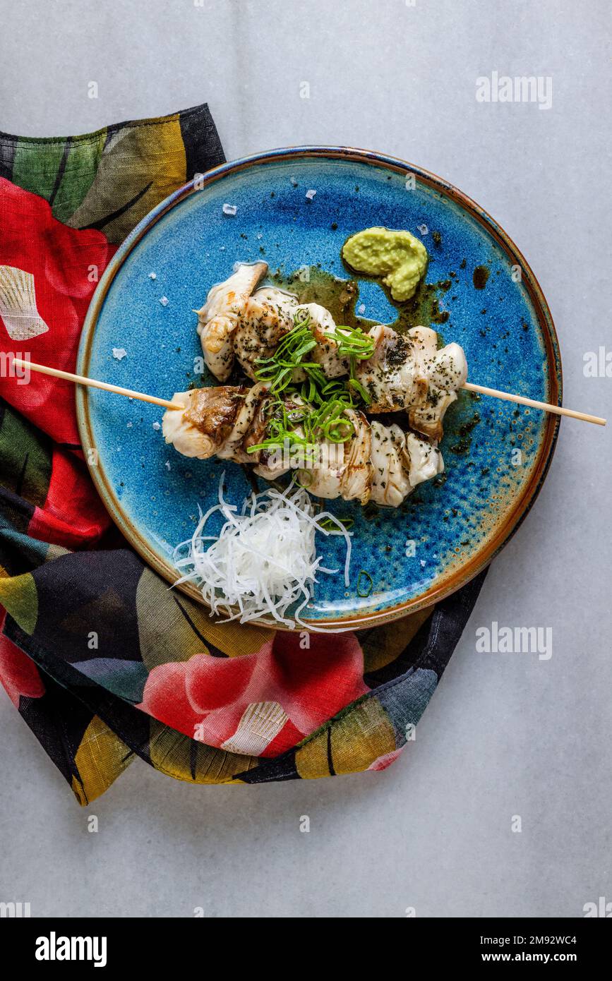 Lemon fish skewer grilled in japanese robata on blue ceramic plate ...