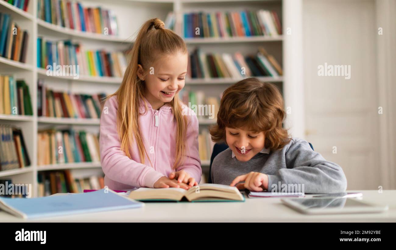 Happy caucasian primary school children reading book together in school ...