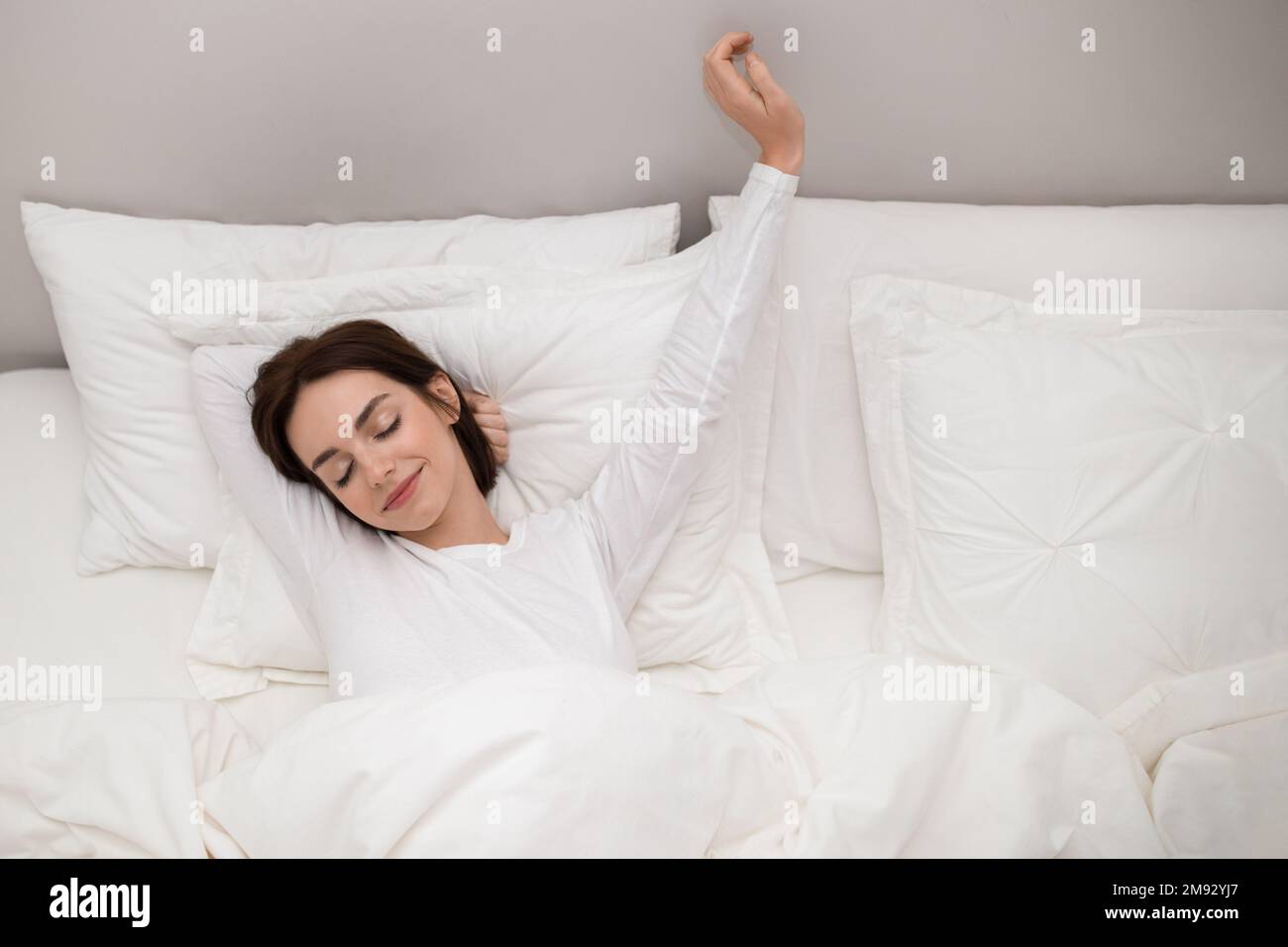 Happy young woman stretching in bed after waking up Stock Photo - Alamy