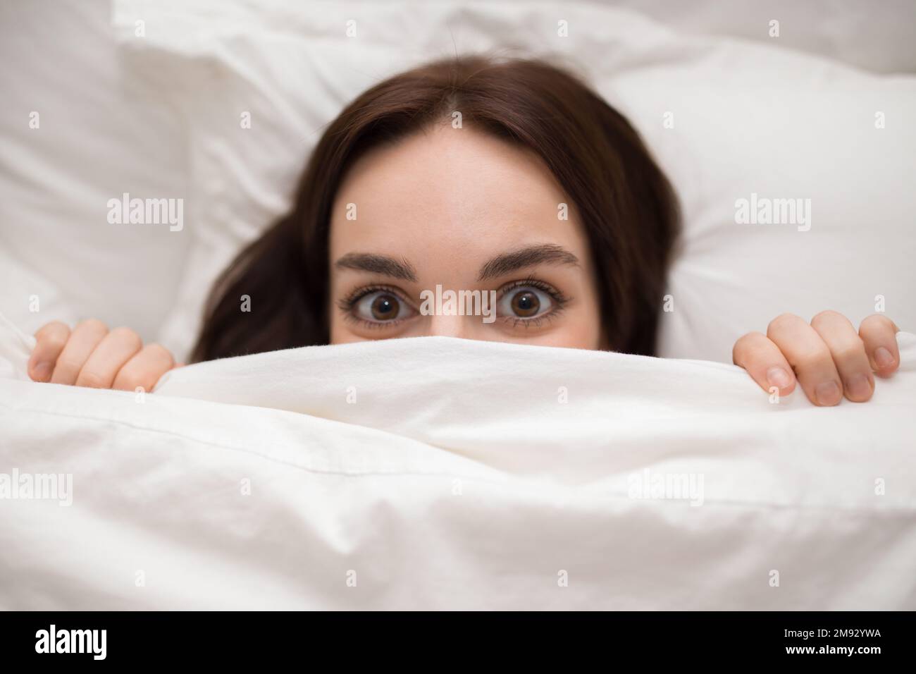 Closeup of young woman hiding under blanket in bed Stock Photo - Alamy
