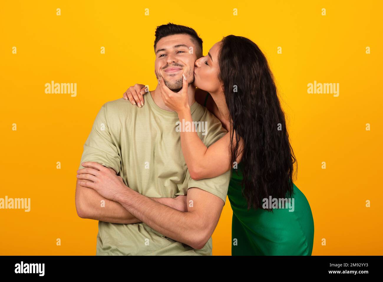 Smiling millennial arab woman in green dress kissing boyfriend, enjoy ...