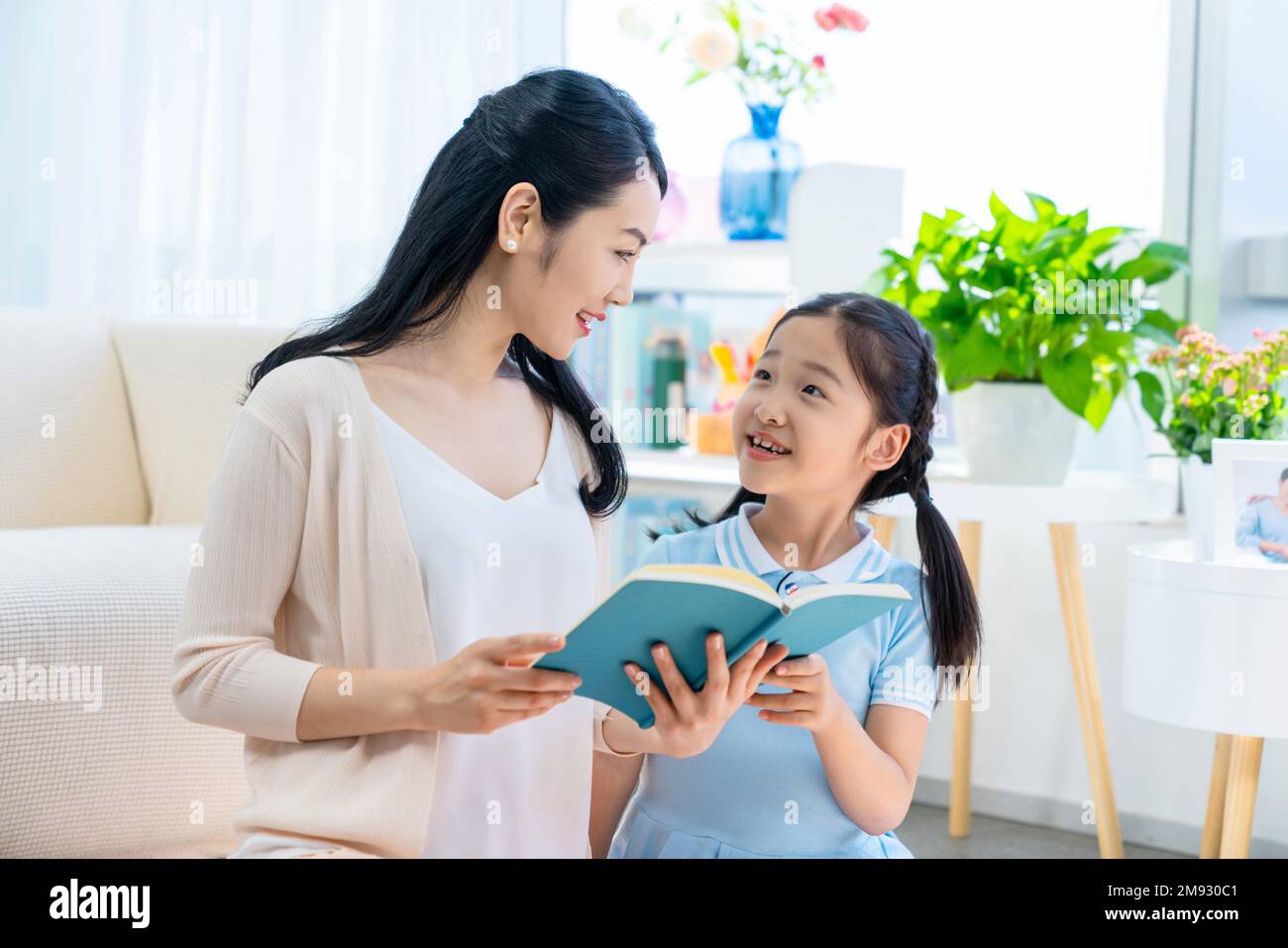 The little girl and her mother read a book together Stock Photo - Alamy