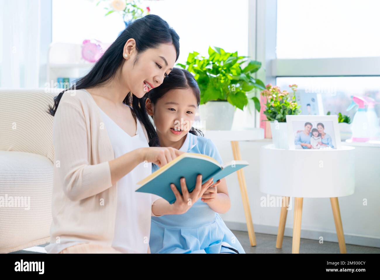 The little girl and her mother read a book together Stock Photo - Alamy