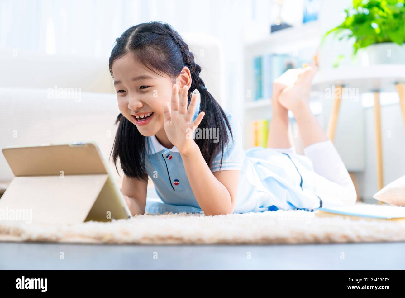 The little girl use tablet computers on the carpet Stock Photo - Alamy