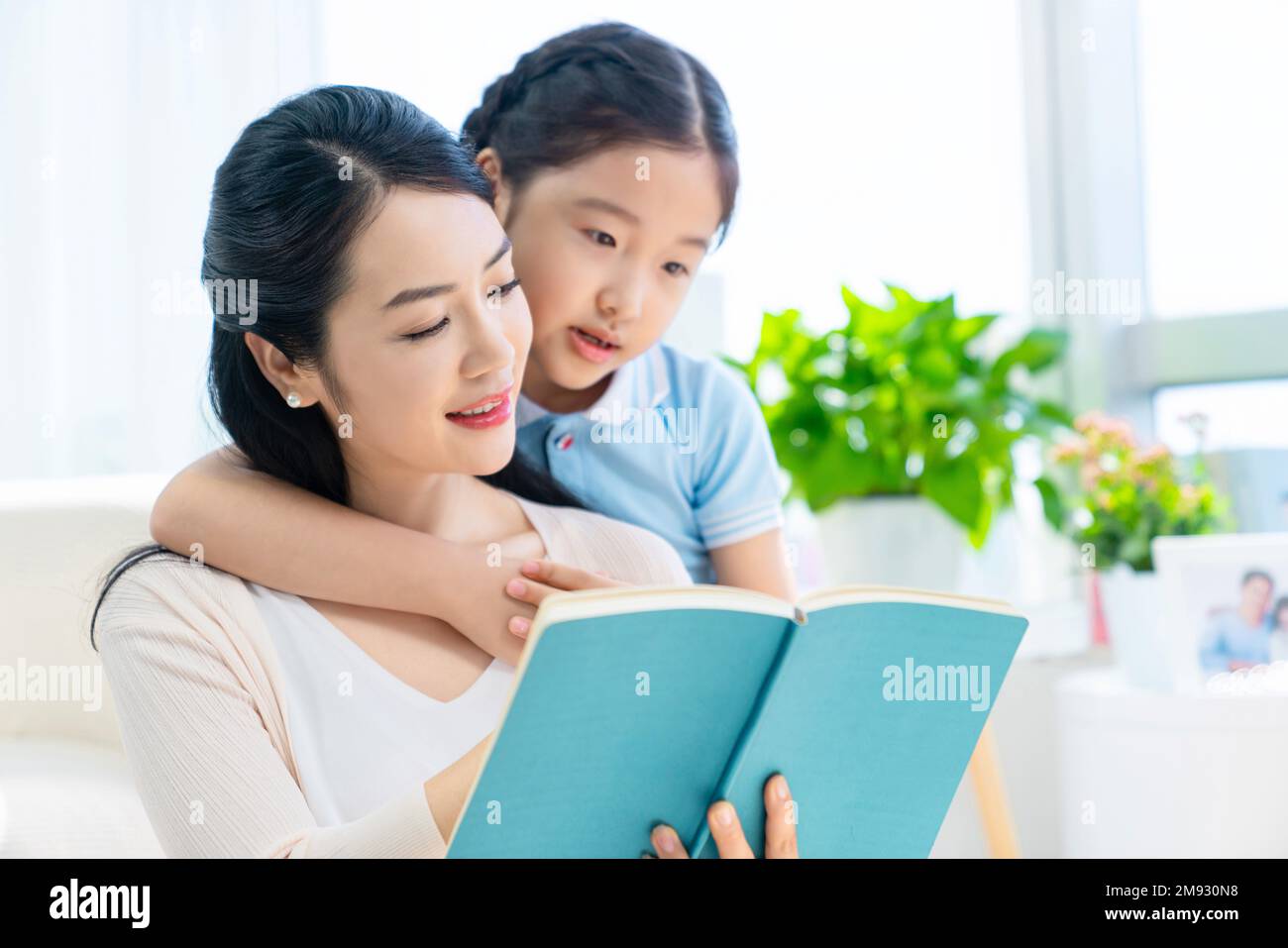 The little girl and her mother read a book together Stock Photo - Alamy