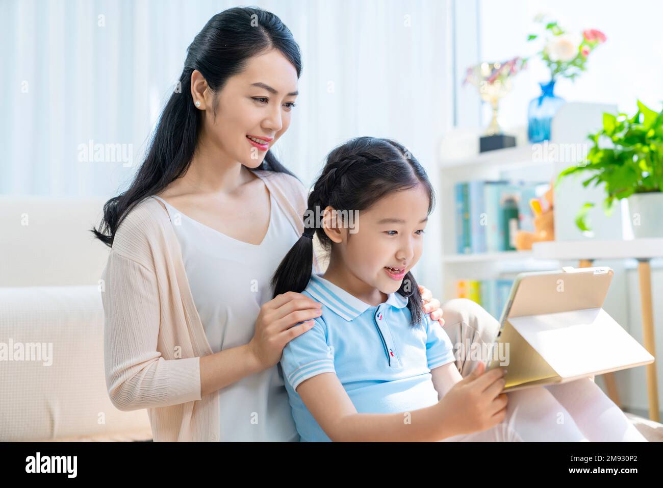 The little girl with her mother to use tablet Stock Photo - Alamy