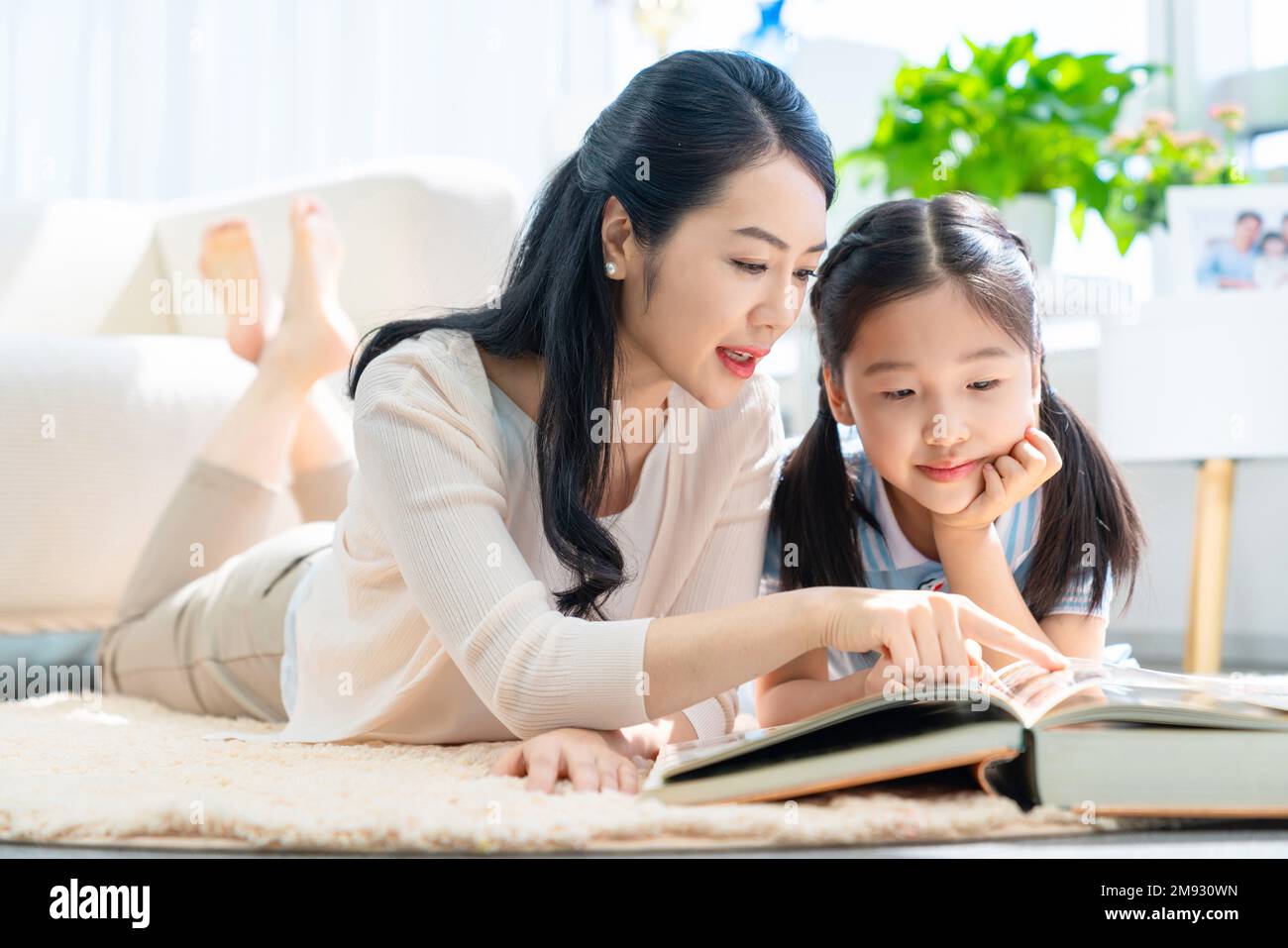 The little girl and her mother read a book together Stock Photo - Alamy