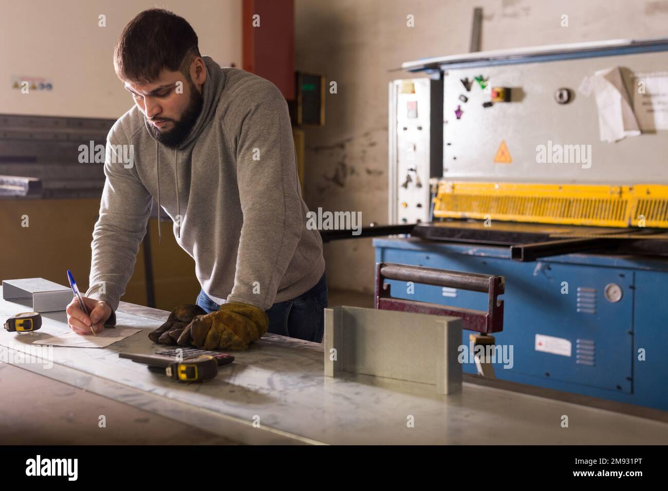 Craftsman of metalworking shop writing in notebook Stock Photo - Alamy