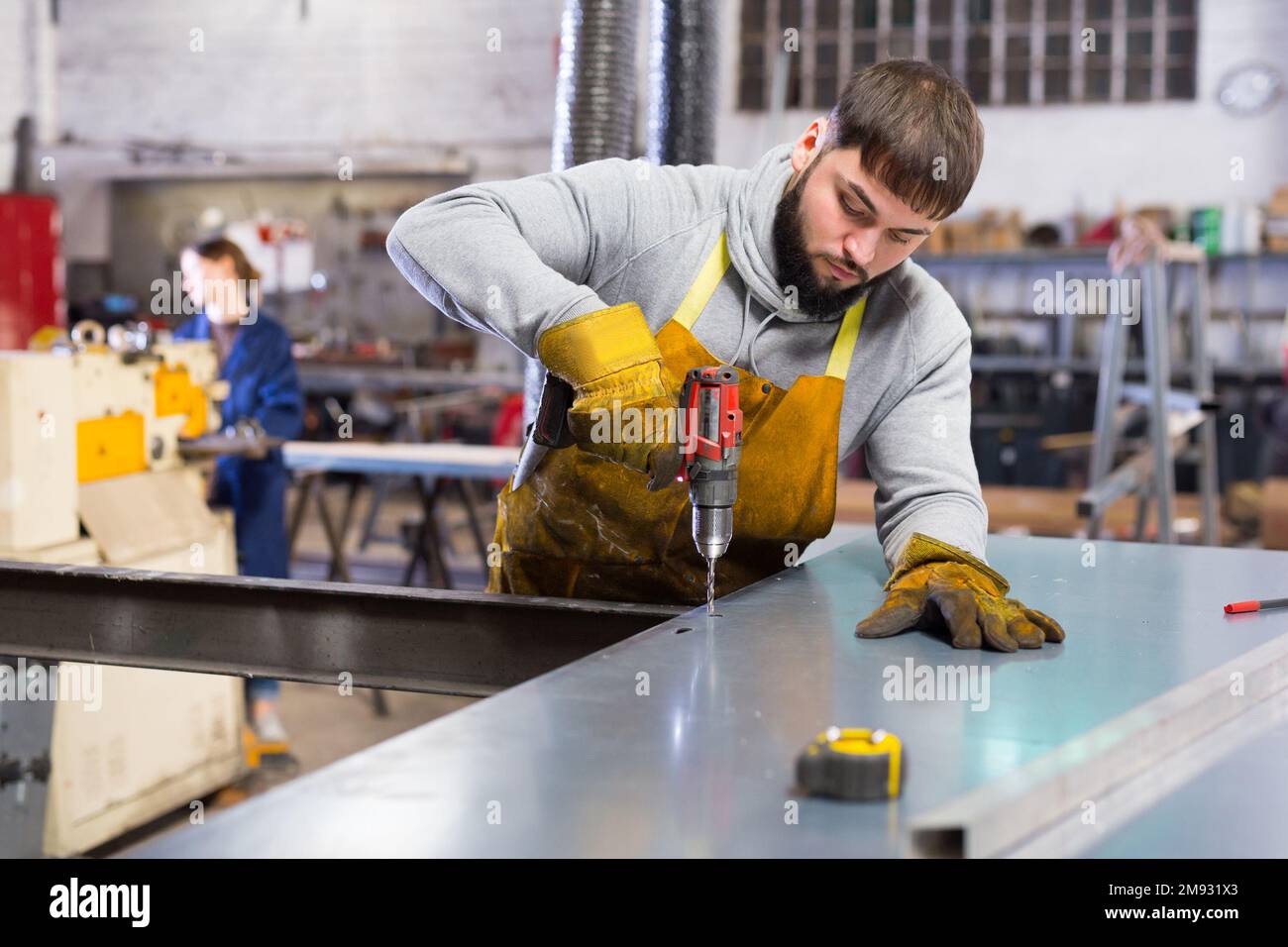 Man engineer drilling metal sheet in workshop Stock Photo - Alamy
