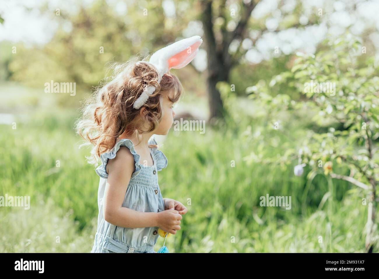 Easter egg hunt. Girl child Wearing Bunny Ears Running To Pick Up Egg ...