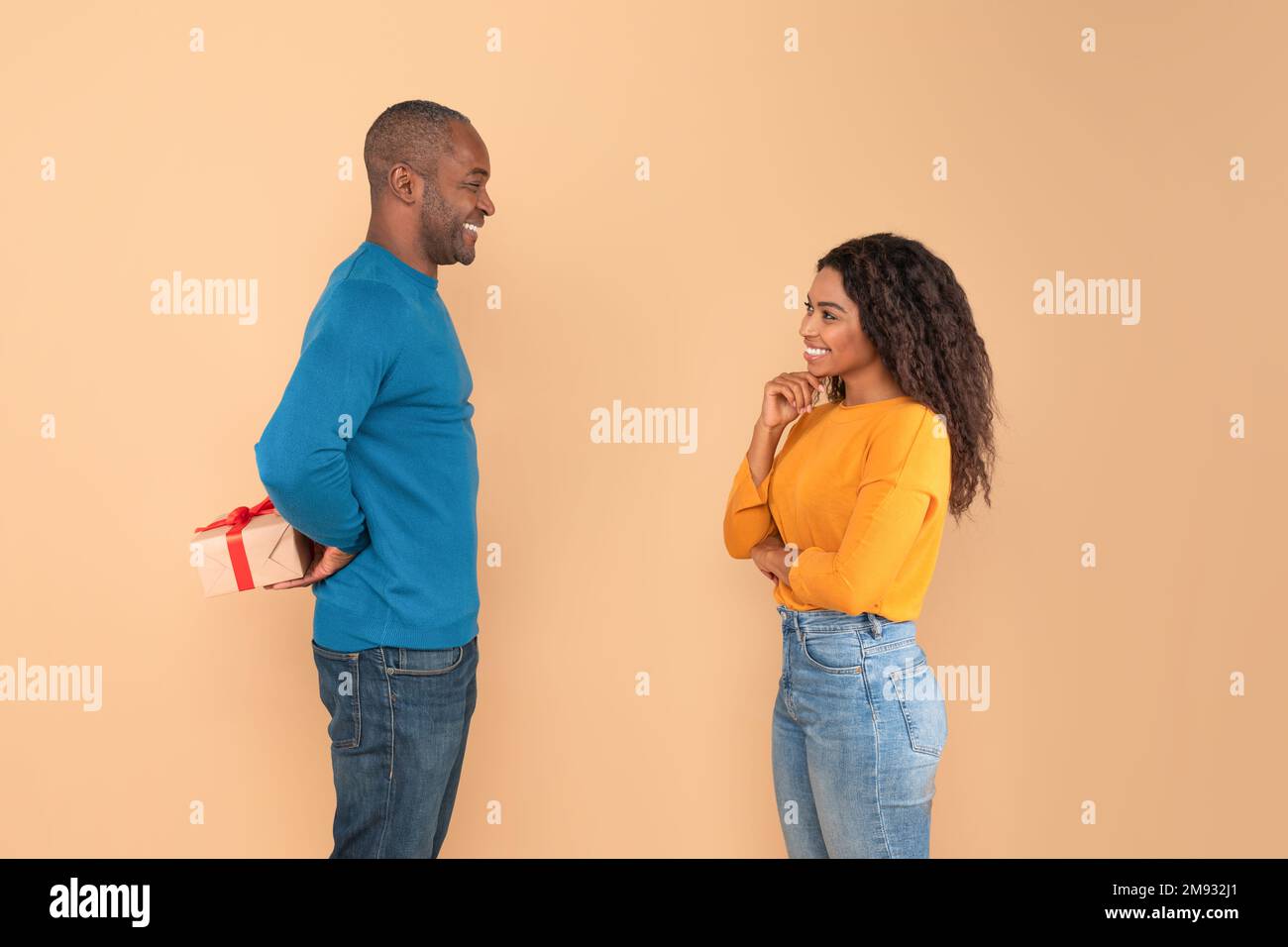 Loving african american man holding wrapped gift box, hiding present ...