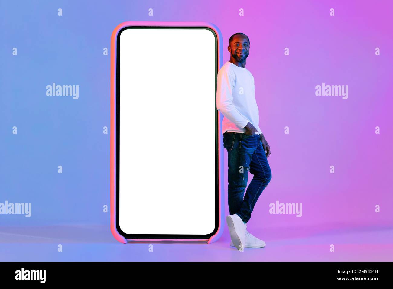 Cheerful black guy posing by big cell phone, mockup Stock Photo - Alamy