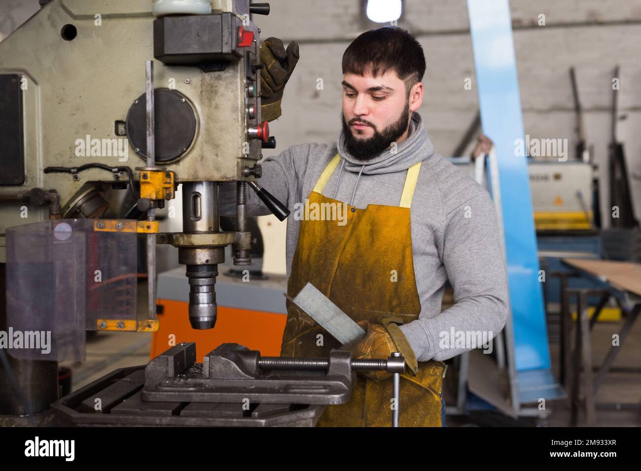 Workman drilling metal parts on stationary machine Stock Photo - Alamy