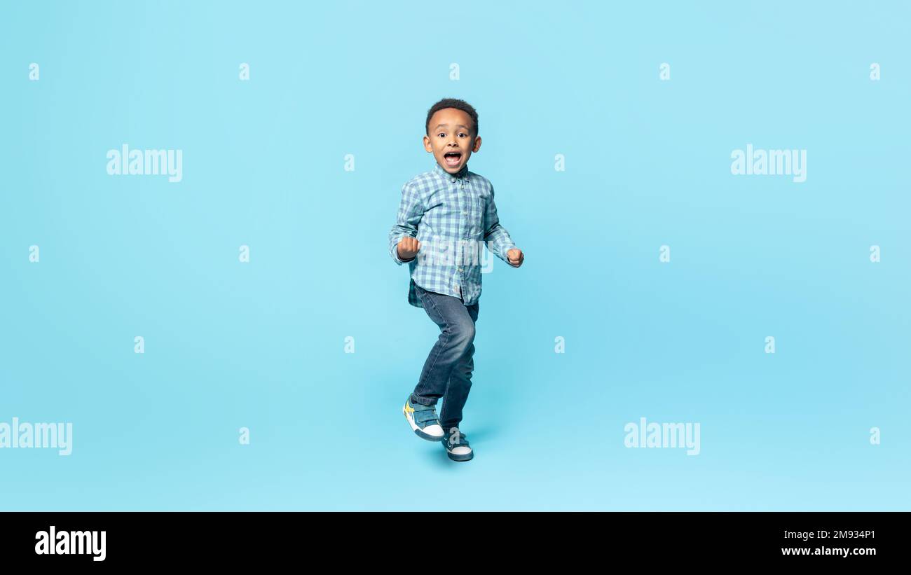 Yes. Happy little black kid boy shaking fists, making winner gesture ...