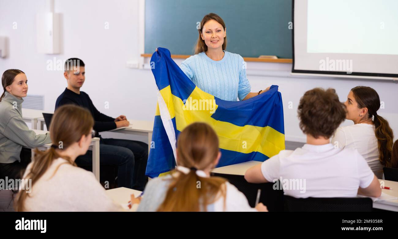 An adult teacher shows the flag of Sweden to students Stock Photo - Alamy