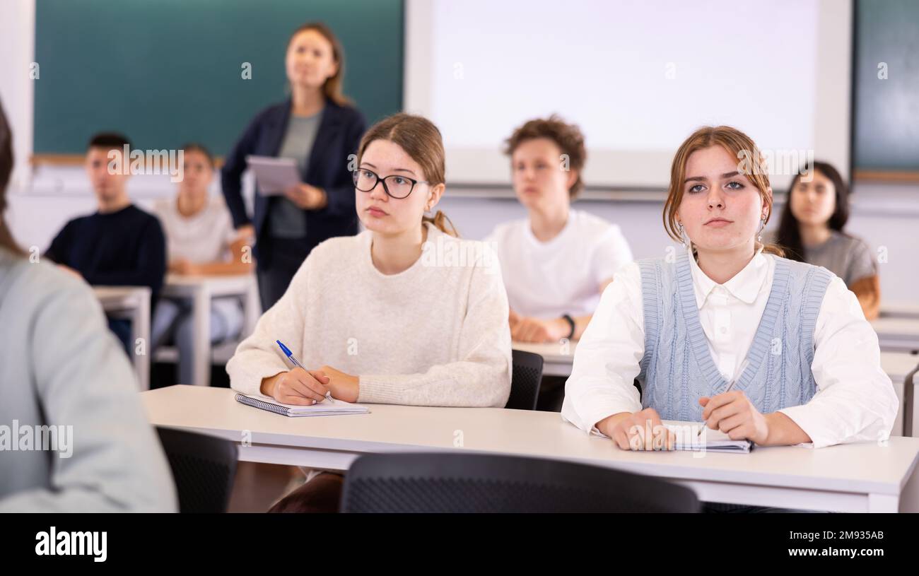 College students sit at desk and write in textbook Stock Photo - Alamy