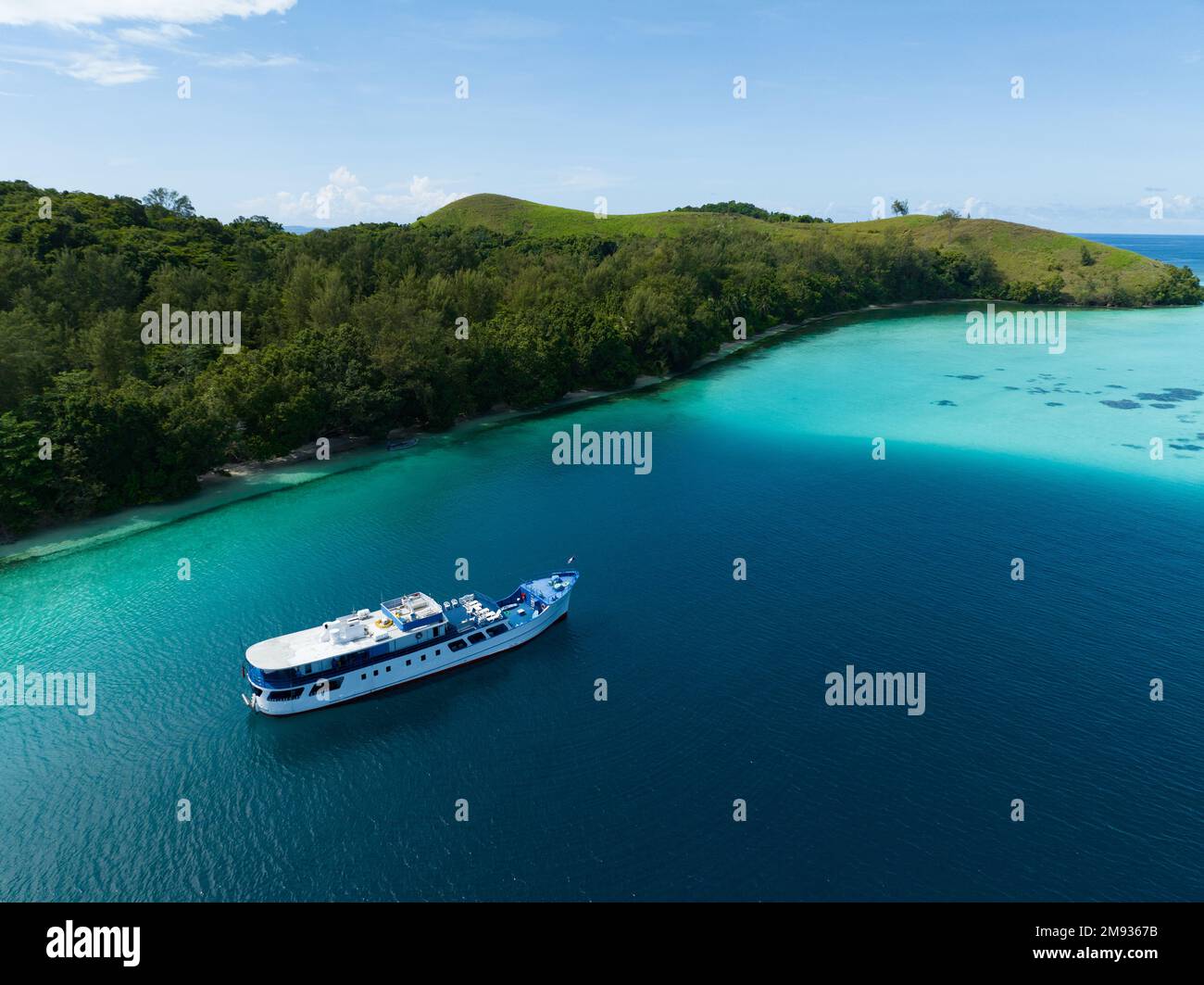 A dive boat sits at anchor next to a remote, idyllic island in the ...