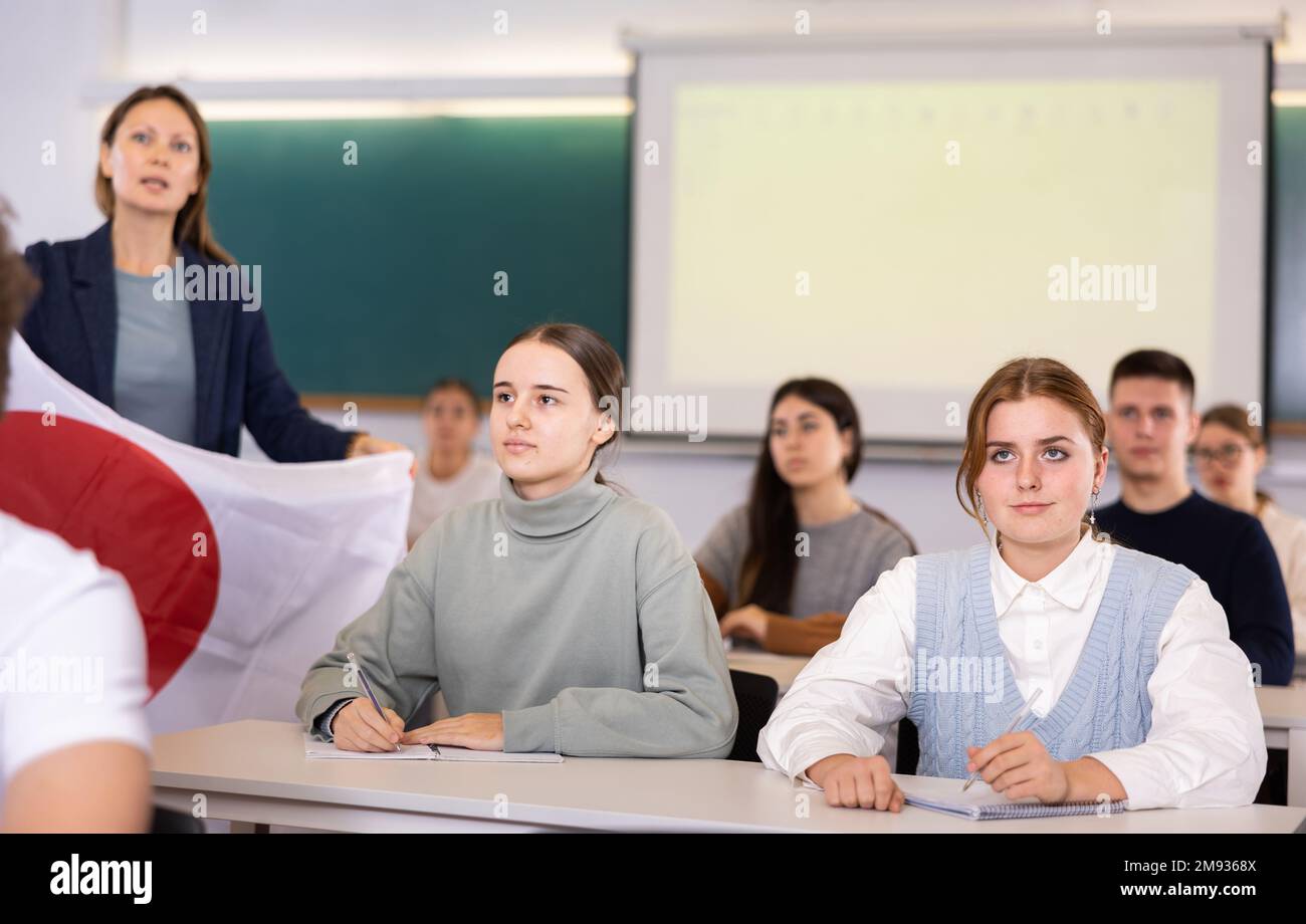 Teacher stands behind students with flag of Japan Stock Photo - Alamy