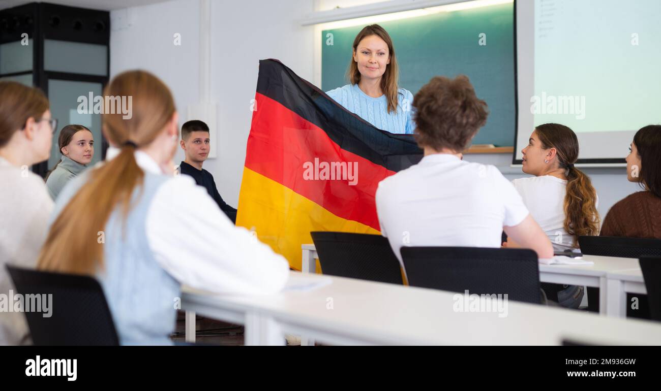 Adult female teacher showing the flag of Germany to the students Stock ...