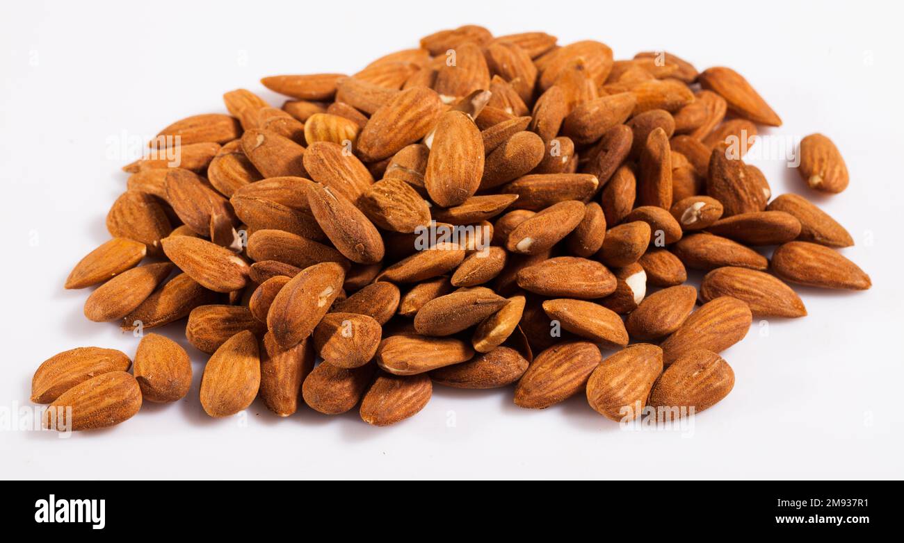Handful of roasted almond nuts on a white surface Stock Photo - Alamy