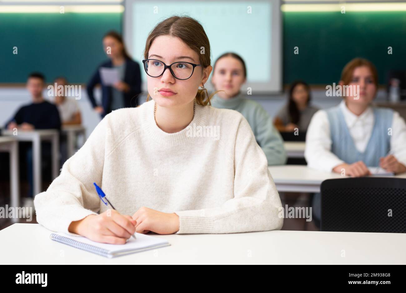 Female student sit at desk and makes notes Stock Photo - Alamy