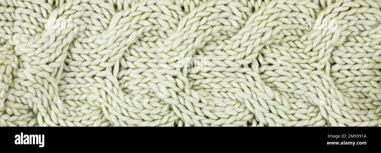 Knitted green background. Large knitted fabric with a pattern. Close-up ...