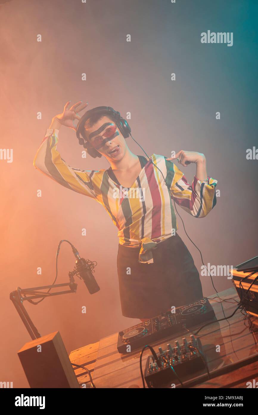 Playful artist sticking tongue out and fooling around, using turntables ...