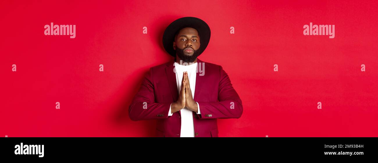Serious african american man showing respect, holding hands together in ...