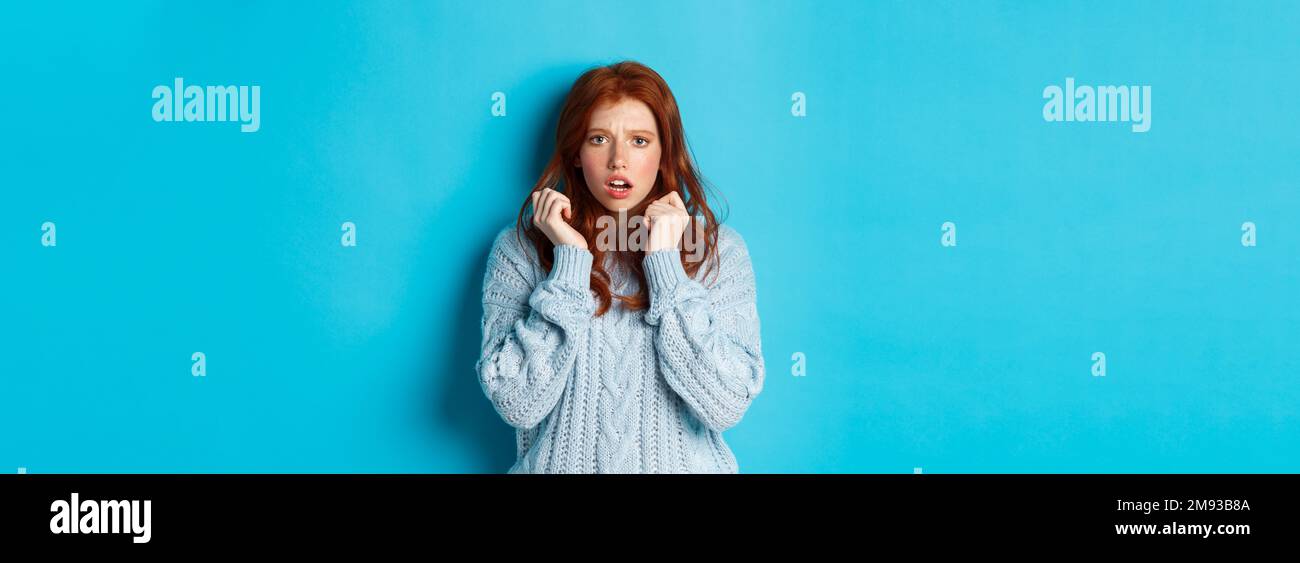 Image of scared teenage girl with red hair, jumping startled and ...