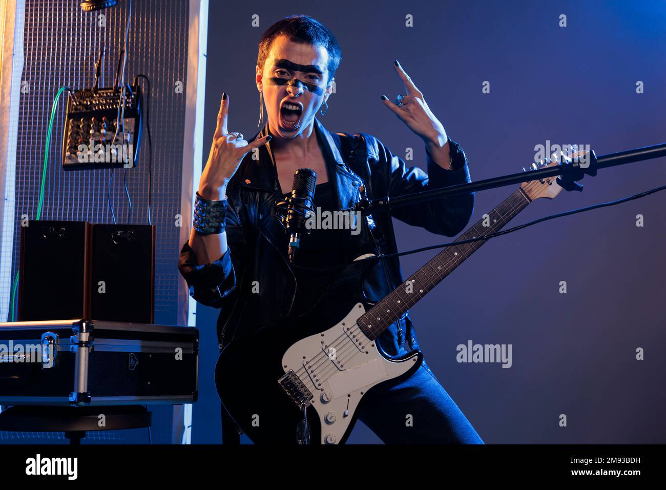 Punk rocker doing rock sign on live performance, singing loud ...