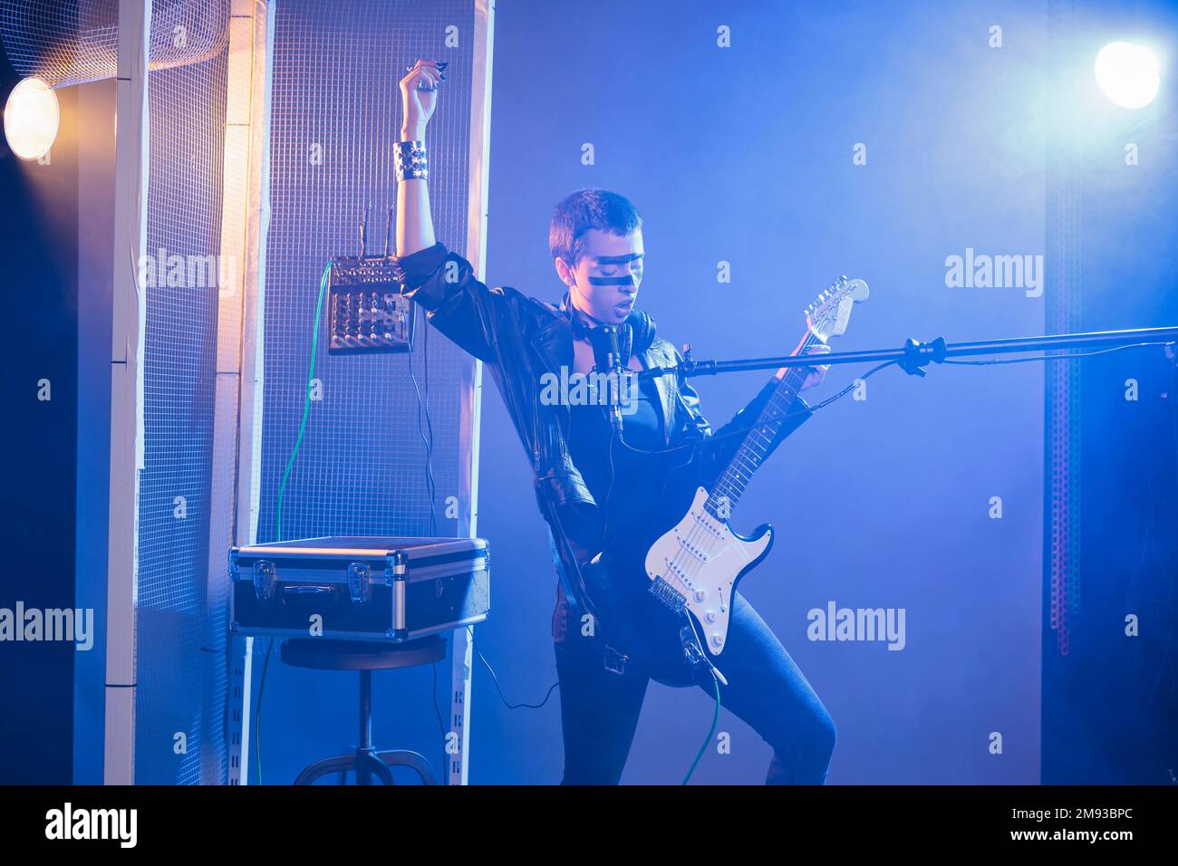 Crazy artist performing live show in studio, playing electric guitar ...