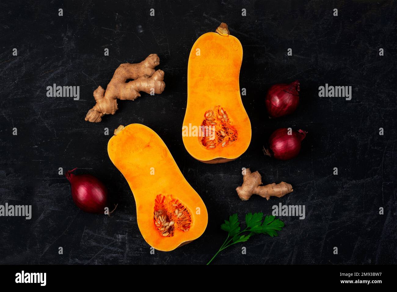 Raw butternut squash with red onion, ginger and parsley leaves on black ...
