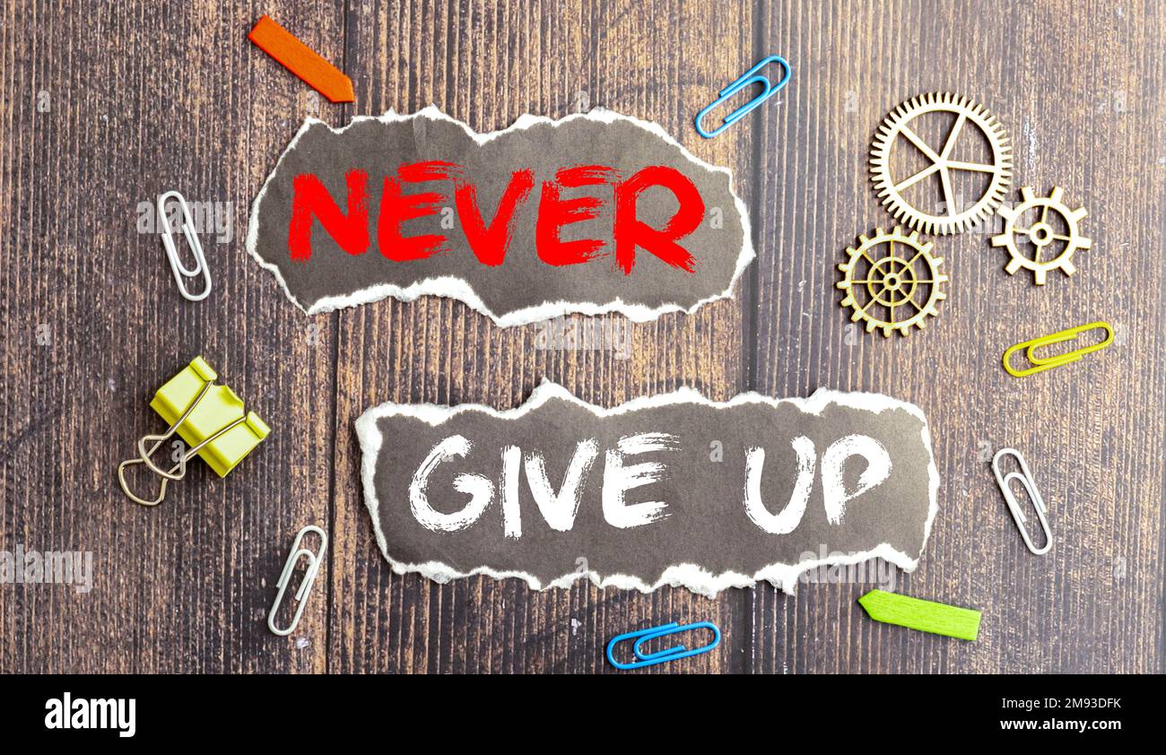 text NEVER GIVE UP on black torn paper Stock Photo - Alamy